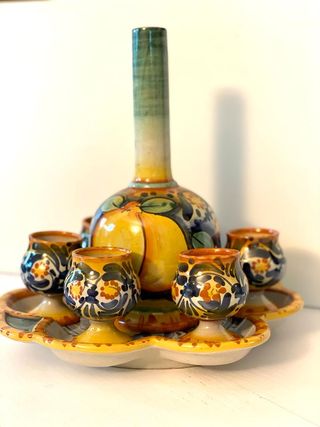 Set con piatto, bicchierini e bottiglia con limoni